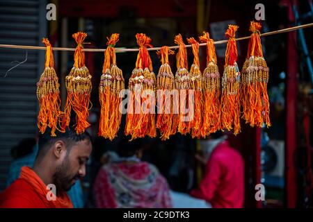 Bunches of rakhis for sale are hanged on a rope in front of a shop ...