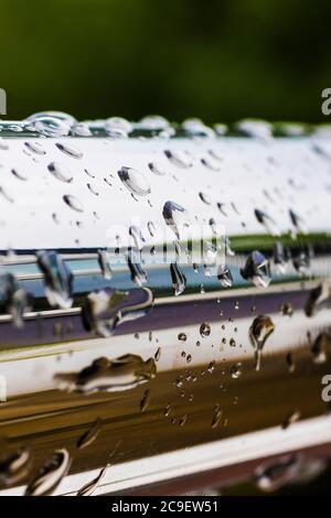 Rain water droplets on steel pipe in rainy day with blur green nature ...