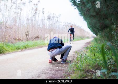 Woman crouching on a road collecting leaves as a cyclist passes Stock ...