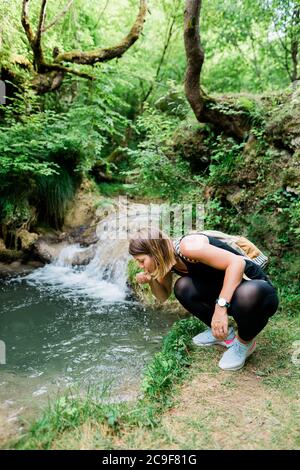 Female hiker drinking water from stream Stock Photo - Alamy