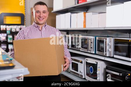 Male customer with packed purchases in household appliances section in ...