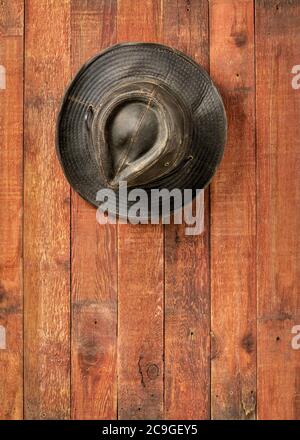 weathered outback oilskin hat hanging on rustic barn wooden wall, copy ...