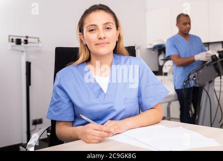 Positive female doctor cosmetologist filling medical forms Stock Photo ...