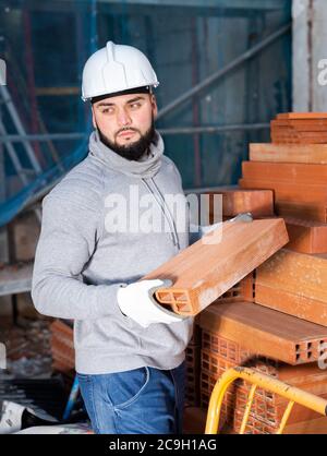Bricks installation. Young man working in uniform at construction at ...