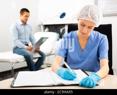 Woman beautician writing notes, man patient on background Stock Photo ...