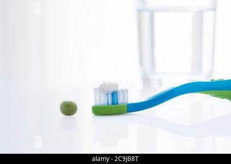 Toothbrush with a pea sized amount of toothpaste against a white ...