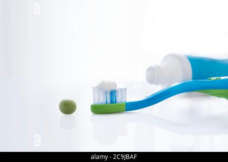 Toothbrush with a pea sized amount of toothpaste against a white ...