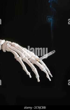 Skeleton hand holding burning cigarette Stock Photo - Alamy
