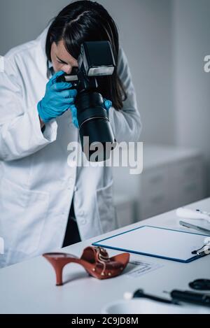 Crime scene. Forensics expert photographing evidence at a crime scene ...