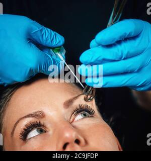 Young woman getting her eyebrow pierced, body piercer wearing blue ...