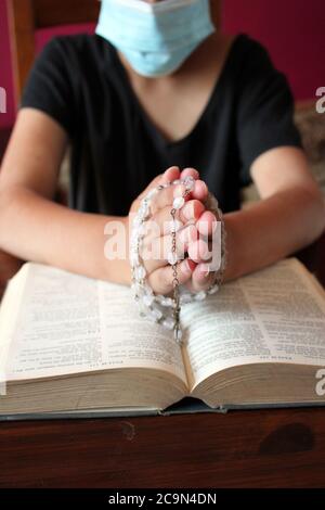 praying hands with bible with coronavirus mask on background with copy ...