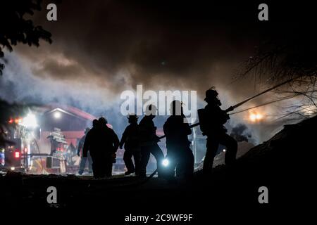 Blazing fire barn with firefighters in shadow Stock Photo - Alamy