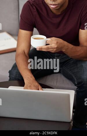 man drinking coffee and surfing the internet with the laptop computer ...
