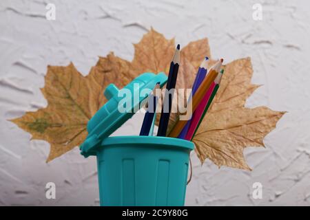 A pencil case in the form of a trash can. It contains colored pencils ...