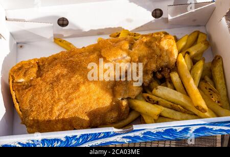Traditional British takeaway meal of battered fish and chips, plus ...