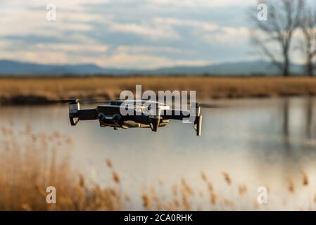 Small modern drone taking picture of lake at sunset Stock Photo - Alamy