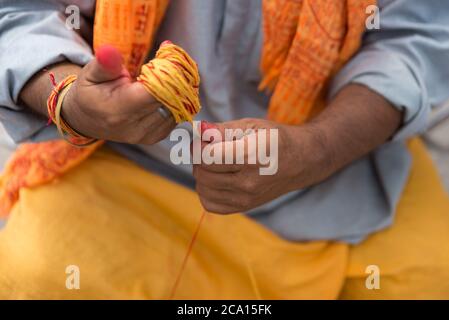 A priest arranging a sacred colorful thread during the festival at the ...