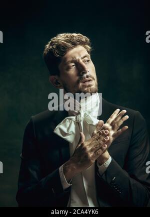 Opium. Young man in suit as Dorian Gray isolated on dark green ...