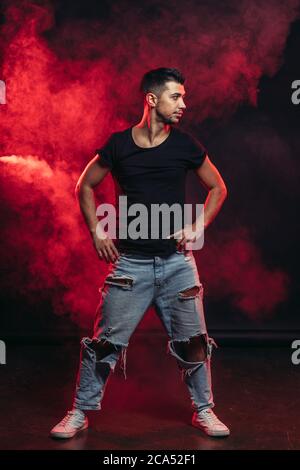 young vigorous male dancing isolated over red smoky space, wearing ...