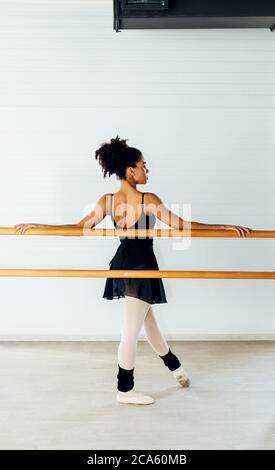 Female ballet dancer resting at barre and mirror in dance studio ...