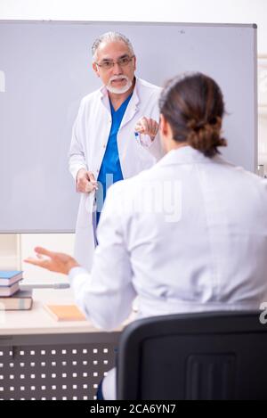 Experienced doctor teaching young assistant using computer Stock Photo ...