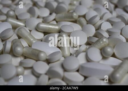Full frame closeup of pile countless white pills and capsules with one ...