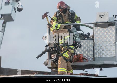 Firefighter using axe on roof Stock Photo - Alamy
