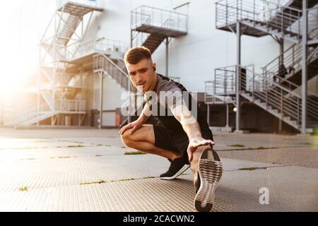 Young sportsman doing exercise while working out at stadium outdoors ...