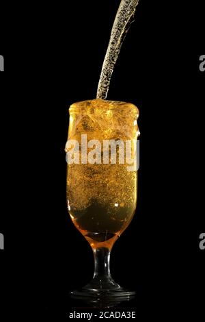 Beer falling into a glass and forming a splash on a black background ...