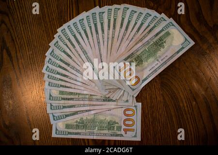 Fanned 100 dollar bills on a woden table Stock Photo - Alamy