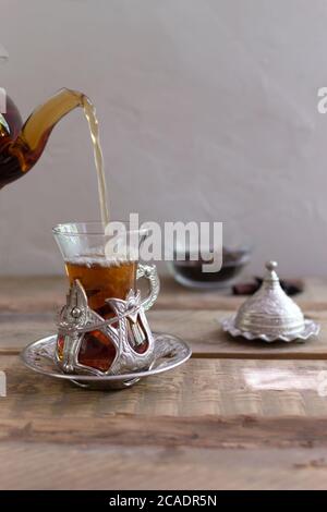 Process of pouring of tasty Turkish tea into glass cup on white ...