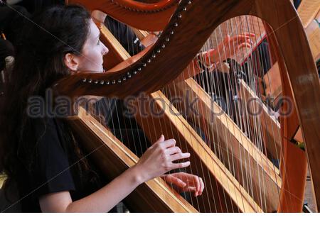 girl playing the harp on stage during a concert Stock Photo - Alamy
