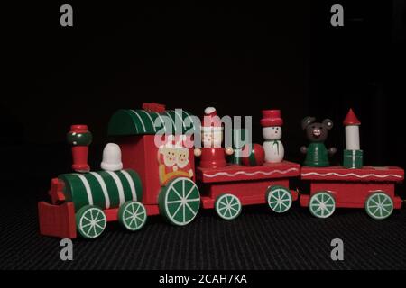 Red children`s Christmas train on a black background. New Year's toy ...