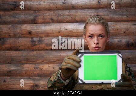 woman soldier using tablet computer against old wooden wall in camp ...