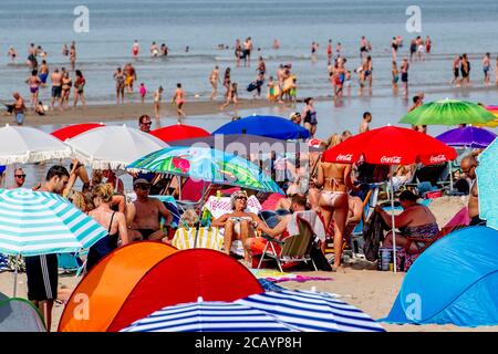 The beach is busy and completely full as people cool off enjoying the ...