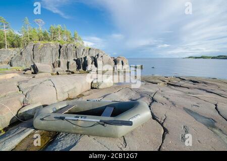 A rubber boat on the sea with rocks in the foreground Stock Photo - Alamy