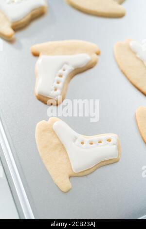 Decorating sugar cookies shaped as figure skates with royal icing Stock ...