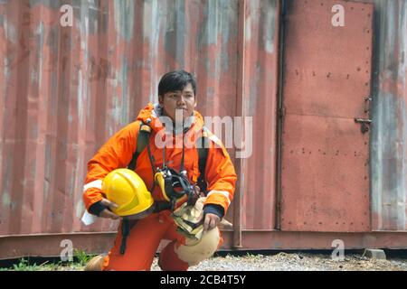 The portrait of young Asian firefighters are wearing orange fire ...