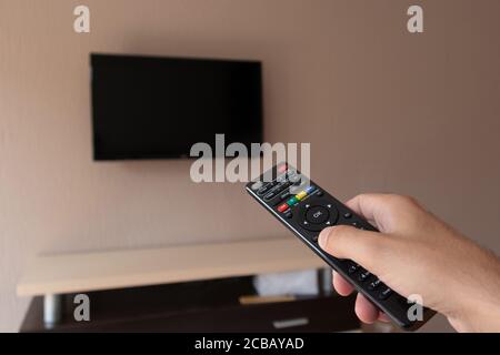 Male hand with TV remote control over green screen. Place for your ...