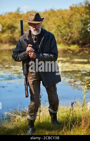 Man with hunting rifle near lake outdoors. Space for text Stock Photo ...