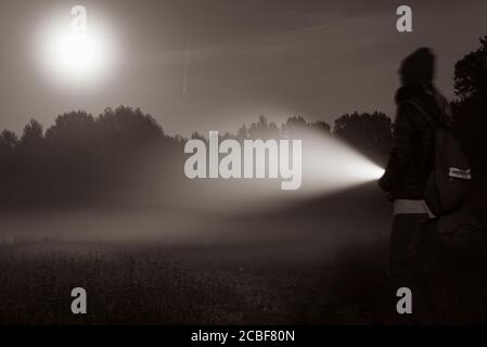 A person with a flashlight on a foggy meadow, with a flashlight in the ...