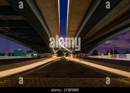 Under a large bridge at night, a massive bridge construction at night ...