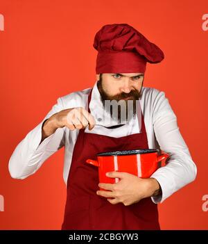 Chef with red saucepan and cutlery. Man with beard Stock Photo - Alamy