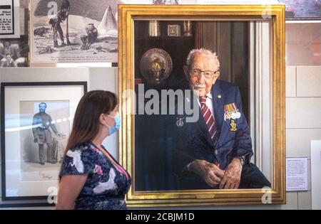 A staff member looks at a portrait of Captain Sir Tom Moore by artist ...