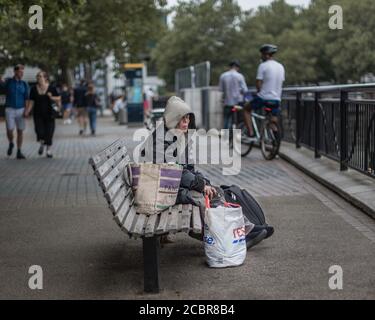 A beggar sits on a bench in front of a church porch His eyes are closed ...