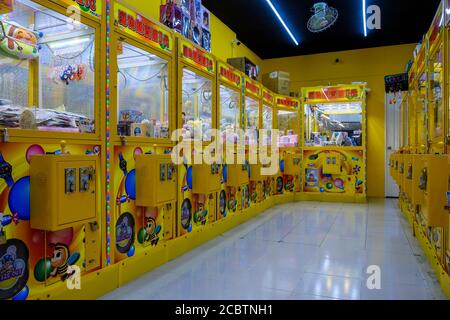 Arcade with claw crane game machines and child playing with coin pusher ...