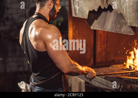 portrait of strong muscular blacksmith man wearing black apron, look ...