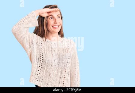 Young blonde woman searching clothes on clothing rack sticking tongue ...