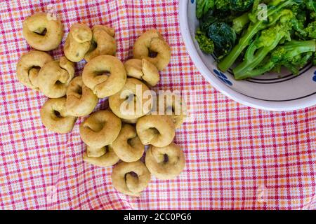 Homemade rapini flavour taralli crackers poured from a glass jar next ...