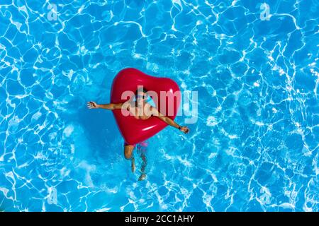 Heart shaped inflatable ring floating in swimming pool, top view ...